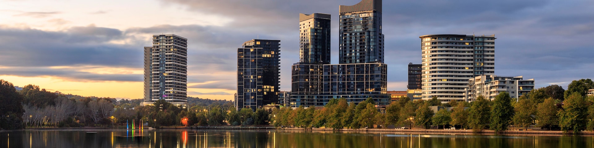 Horizonte urbano refletido em um lago calmo, com edifícios modernos e altos.