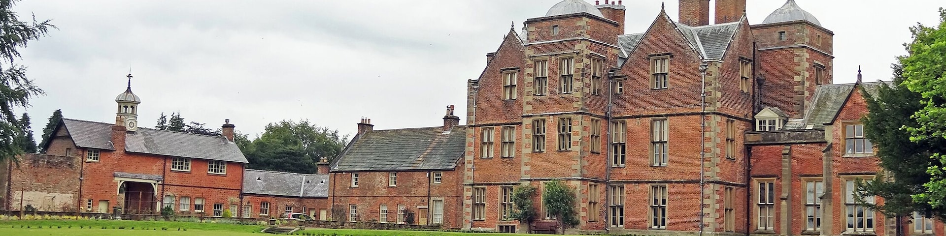a general view of the back of the Grade I listed Kiplin Hall from beside the lake