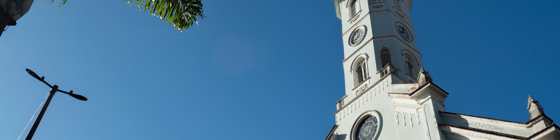 Uma torre de igreja com um relógio e uma cruz no topo.