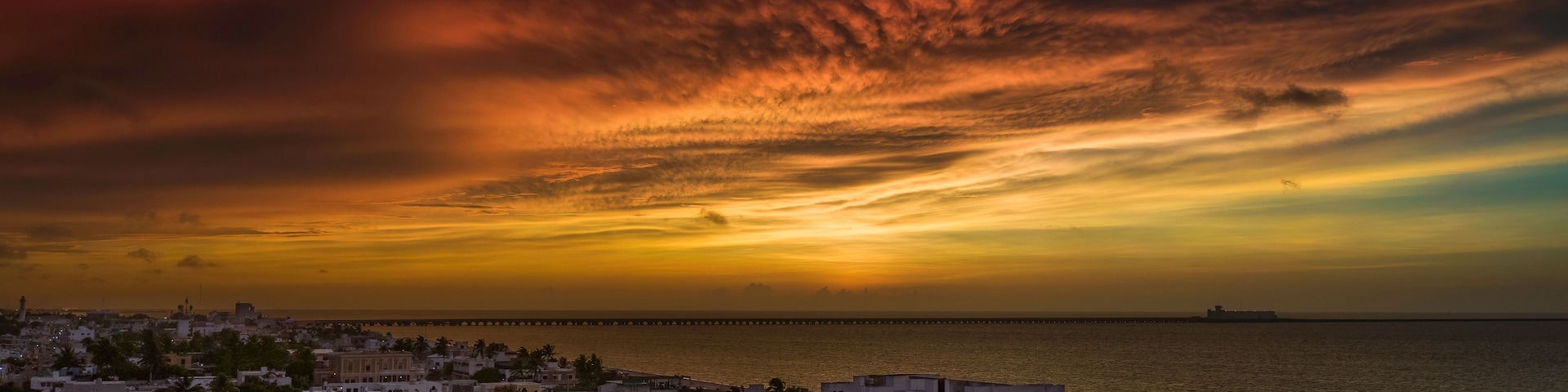 Paisagem urbana costeira ao pôr do sol, com um céu dramático.