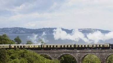 Um trem atravessando uma ponte sobre a água, com vapor subindo.