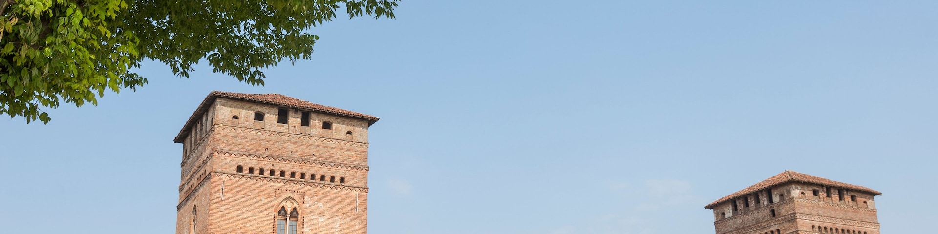 Um edifício histórico de tijolos com duas torres e janelas em arco.
