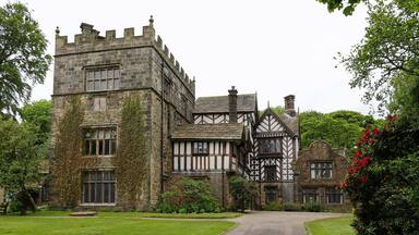 Um edifício de pedra grande com uma torre e uma casa em estilo Tudor.