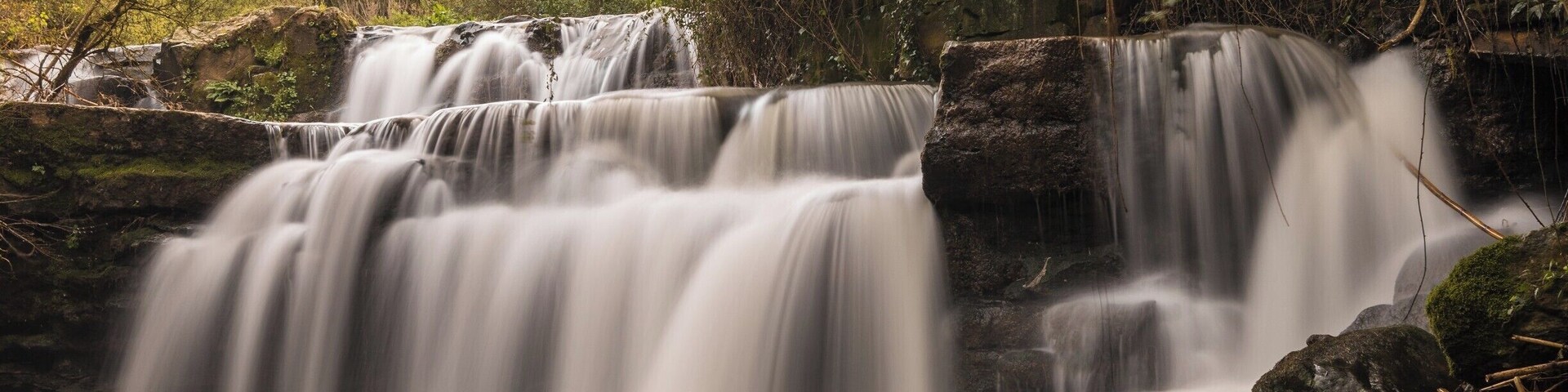Hidden behind the motorway, there are a series of waterfalls in a small river called Ribeira do Adrião. To get there, you must park close to the water residue treatment station and then cross the river, walk about 300 mts till you start descending. Then you'll found the remains of a old house, there you can go down to the river where you'll found the waterfall.