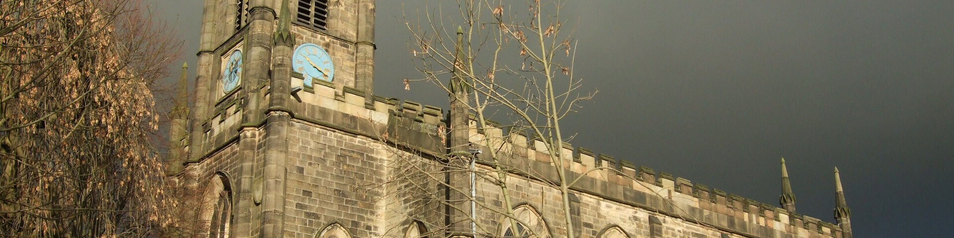 Uma igreja histórica com uma torre do relógio e janelas em arco.