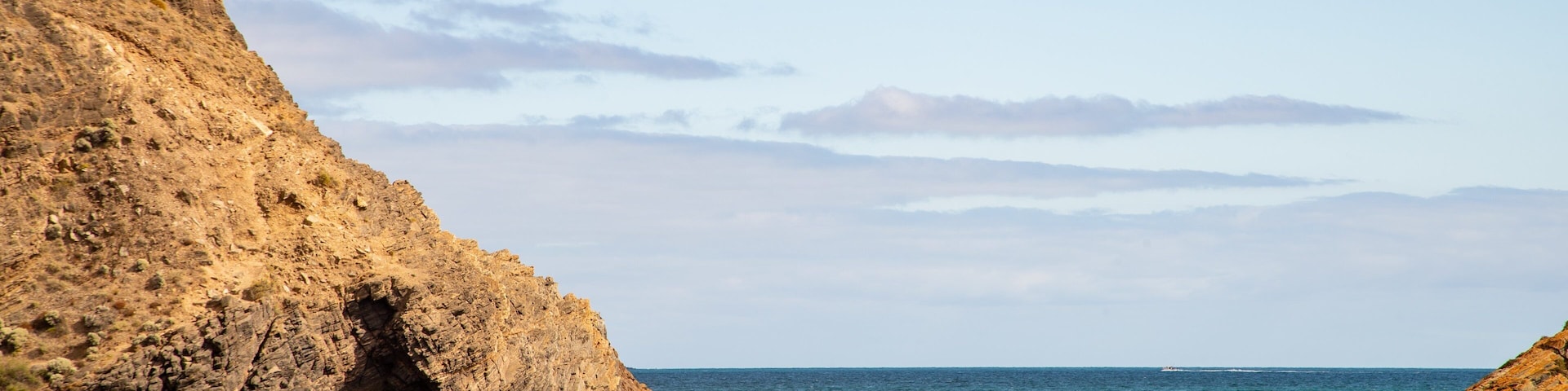 Litoral rochoso com falésias e mar azul cristalino.