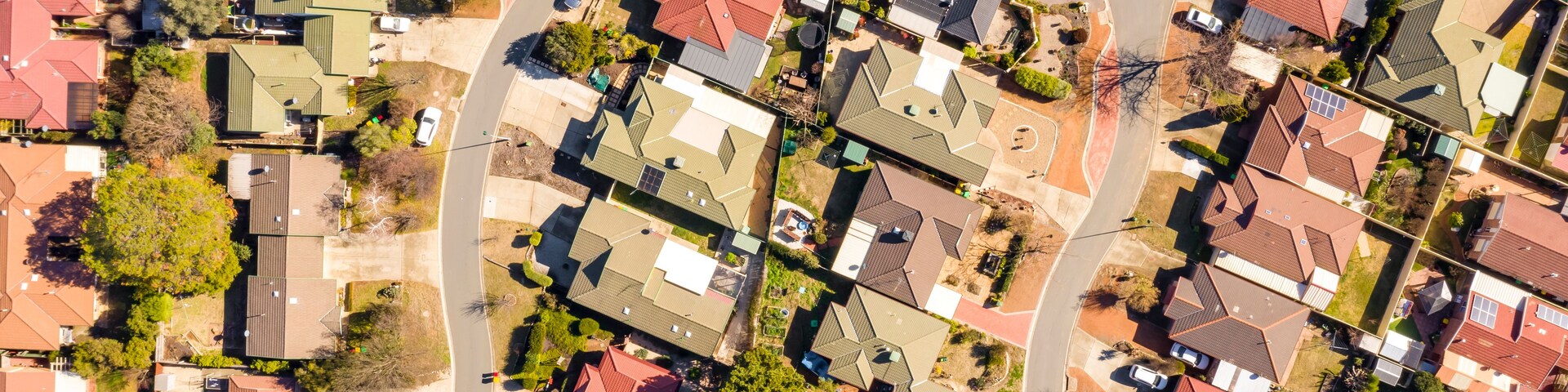 Vista aérea de um bairro residencial com casas, ruas e áreas verdes.