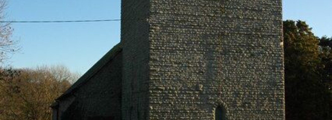 Uma igreja de pedra com uma torre do relógio e um céu azul límpido.