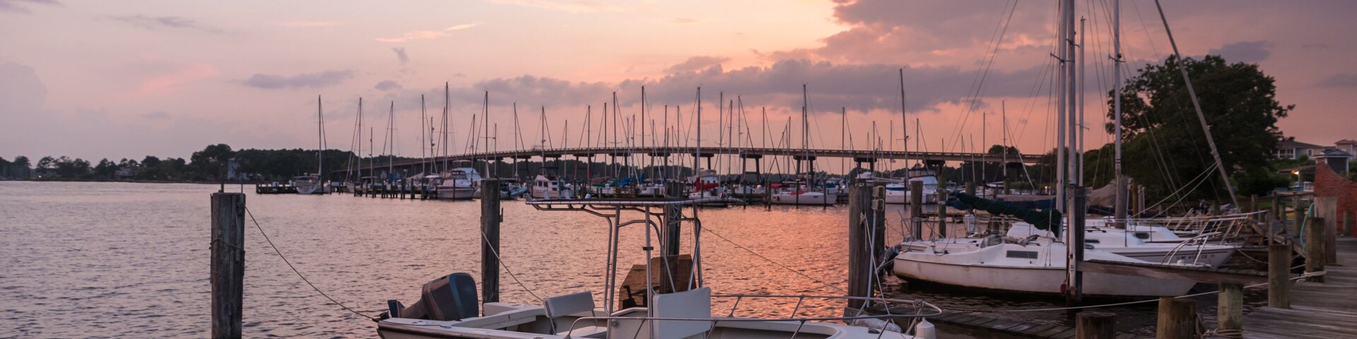 Uma marina com barcos atracados em cais de madeira ao pôr do sol.