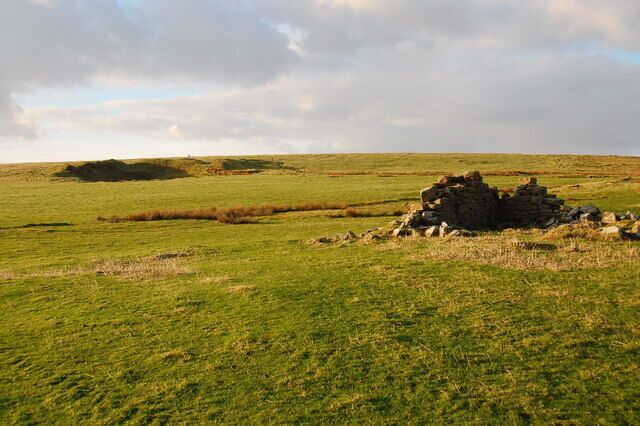 Um campo gramado com uma estrutura de pedra ao centro.