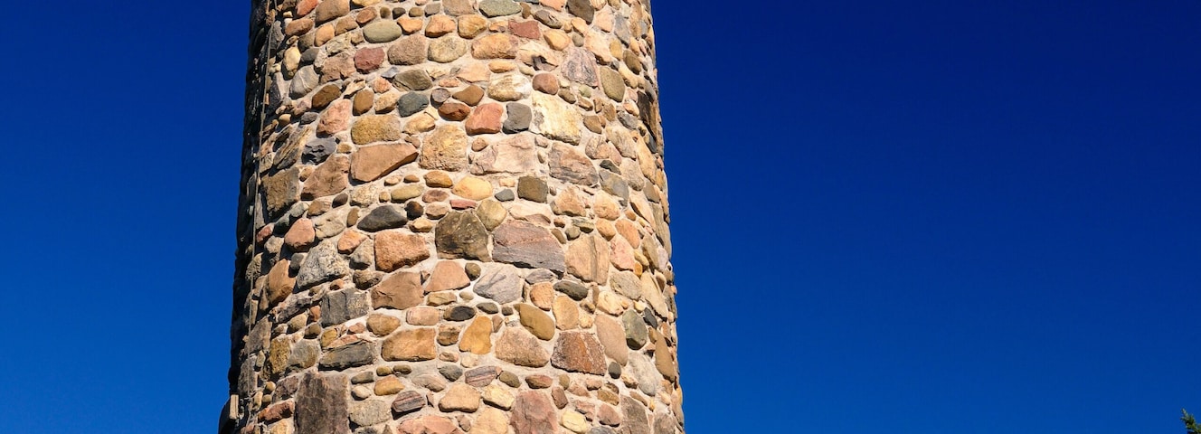 Uma torre de pedra com topo circular e uma pequena janela.