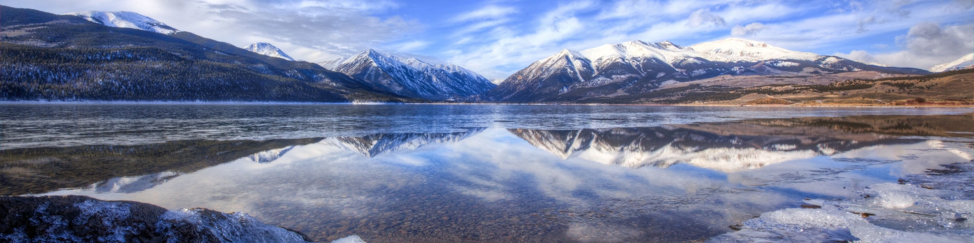Um lago congelado com montanhas ao fundo.