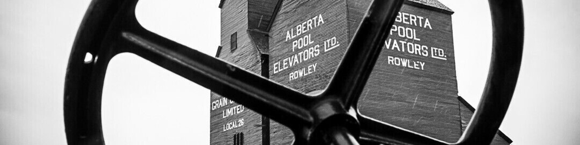 Um grande edifício industrial com placas indicando Alberta Pool Elevators Ltd. e Grain United Locals.