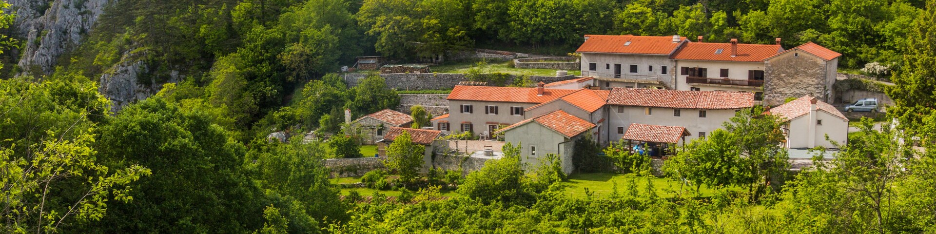 Uma vila aninhada num vale, com casas em socalcos e vegetação exuberante.