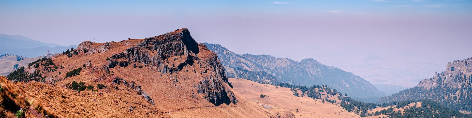 Paisagem montanhosa acidentada com picos rochosos e vegetação escassa.