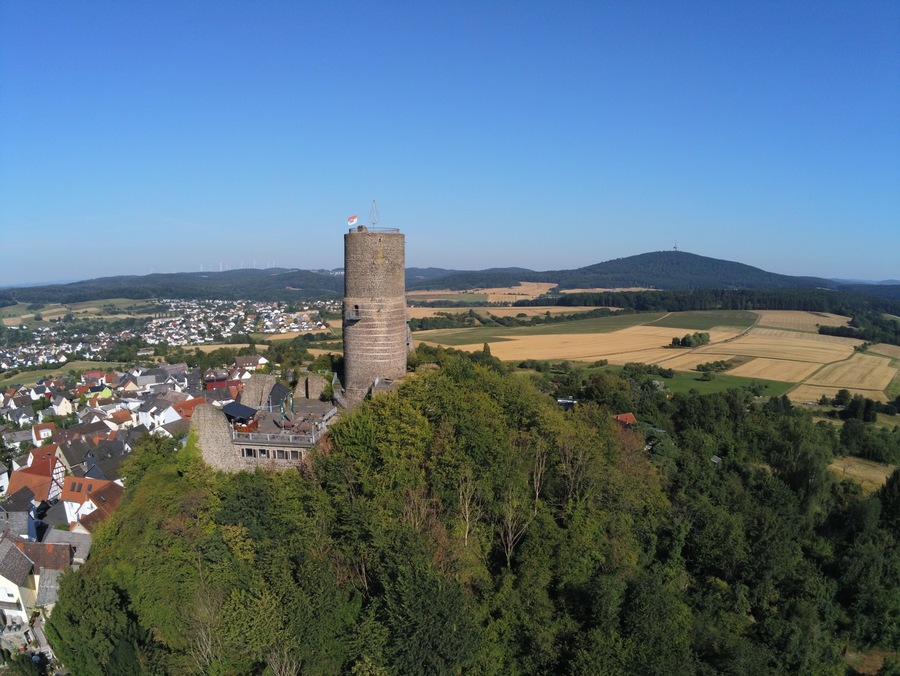 Uma torre histórica rodeada por uma aldeia e colinas ondulantes.