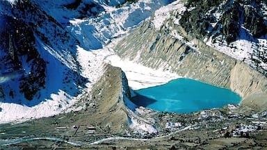 Paisagem montanhosa com um glaciar e uma pequena aldeia.