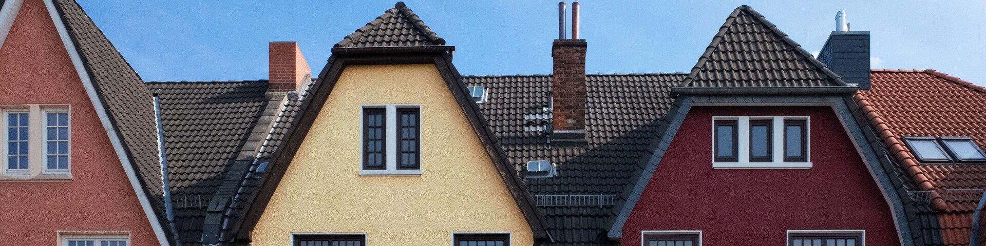 Uma fileira de casas coloridas com estilos arquitetônicos distintos e um céu azul límpido.