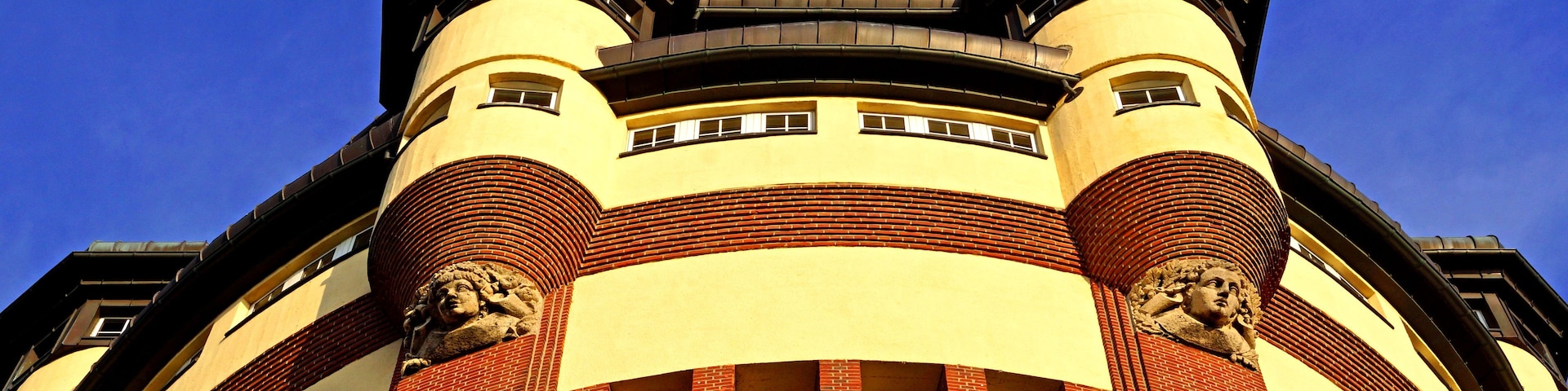Um edifício com fachada curva, detalhes em tijolo e duas estátuas de leão.
