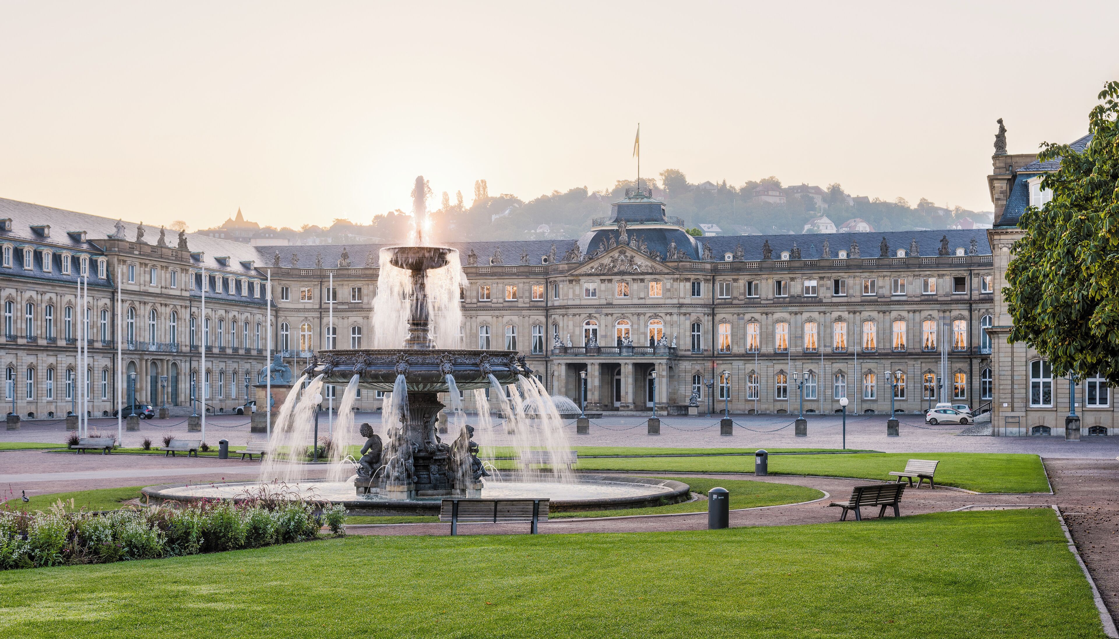 Um edifício histórico imponente com uma fonte central e jardins bem cuidados.