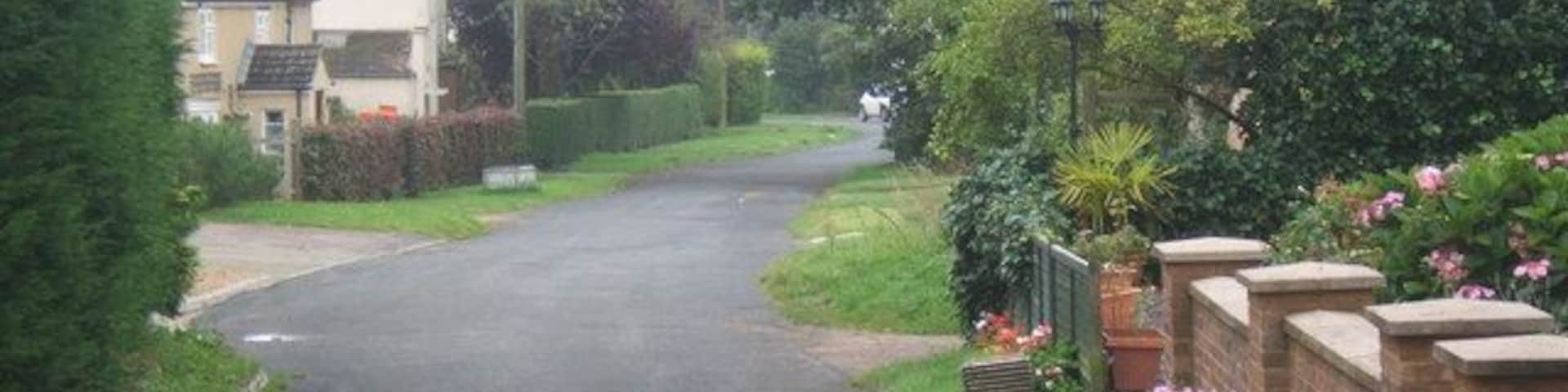 Village street, Brington The dead end lane gets narrower towards the church. This is looking back down through the village.