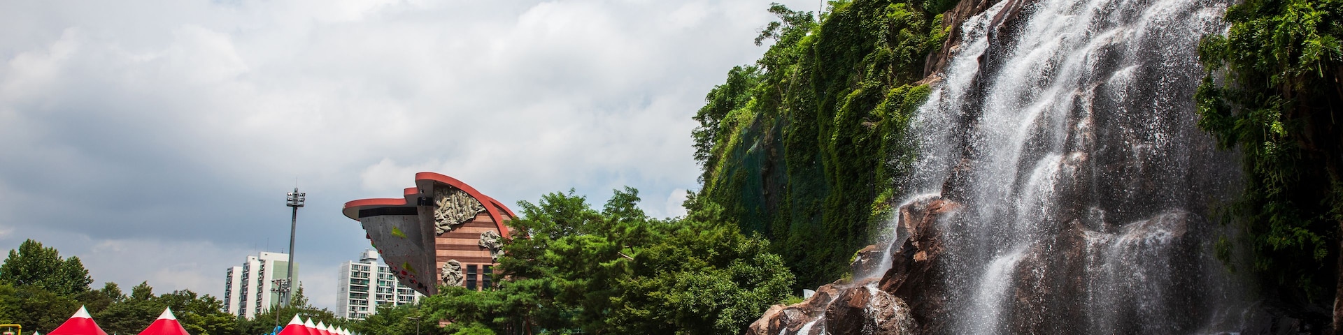 Uma cascata, uma formação rochosa e um edifício com telhado curvo.
