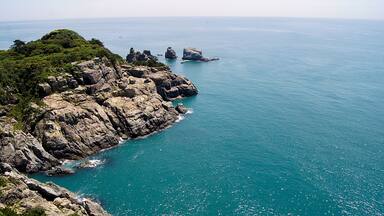 Paisagem costeira com falésias rochosas e águas azul-turquesa.