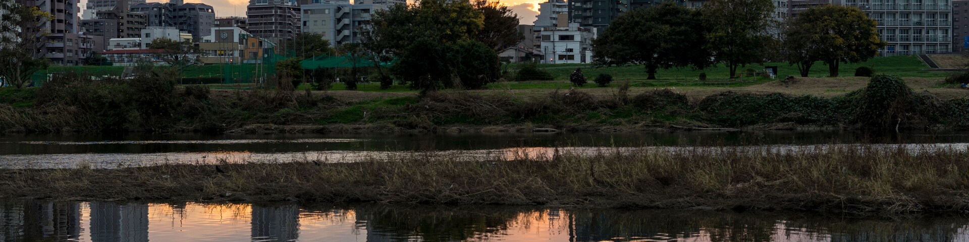 Linha do horizonte urbana com edifícios altos e um corpo d'água tranquila refletindo o céu.