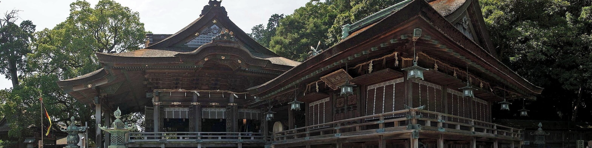 Um templo japonês tradicional com estrutura de madeira, rodeado por árvores.