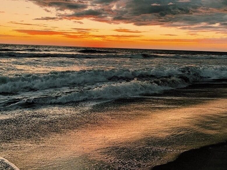 Uma praia com ondas ao pôr do sol.