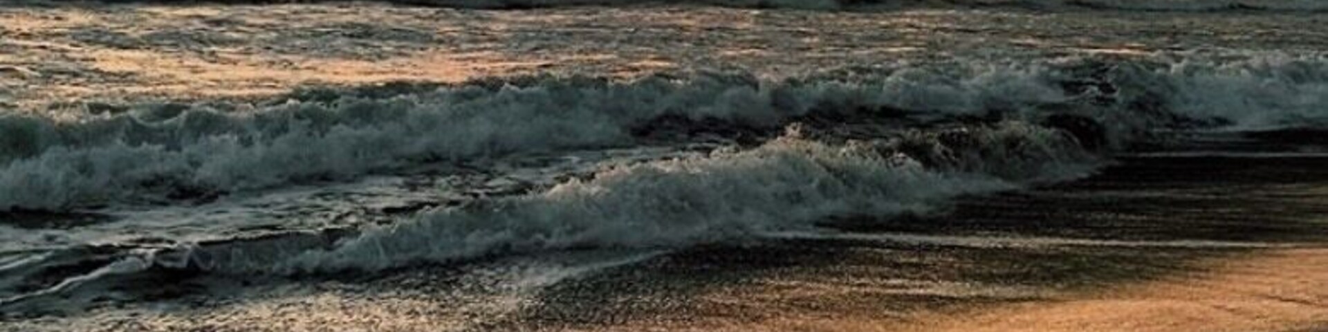 Uma praia com ondas ao pôr do sol.