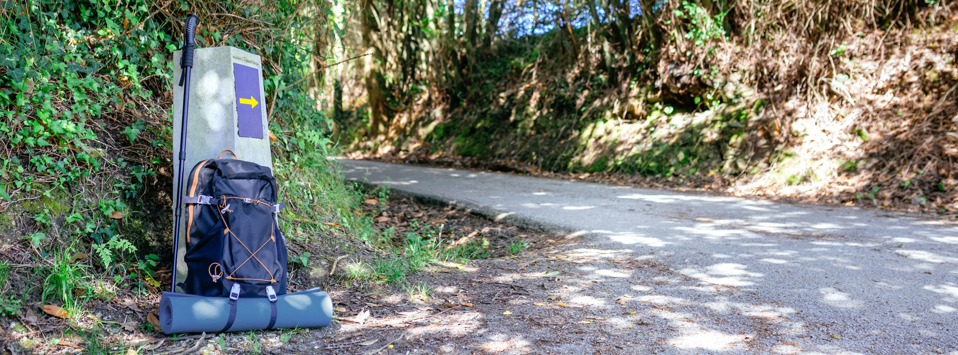 Uma estrada com um sinalizador e uma mochila no chão.