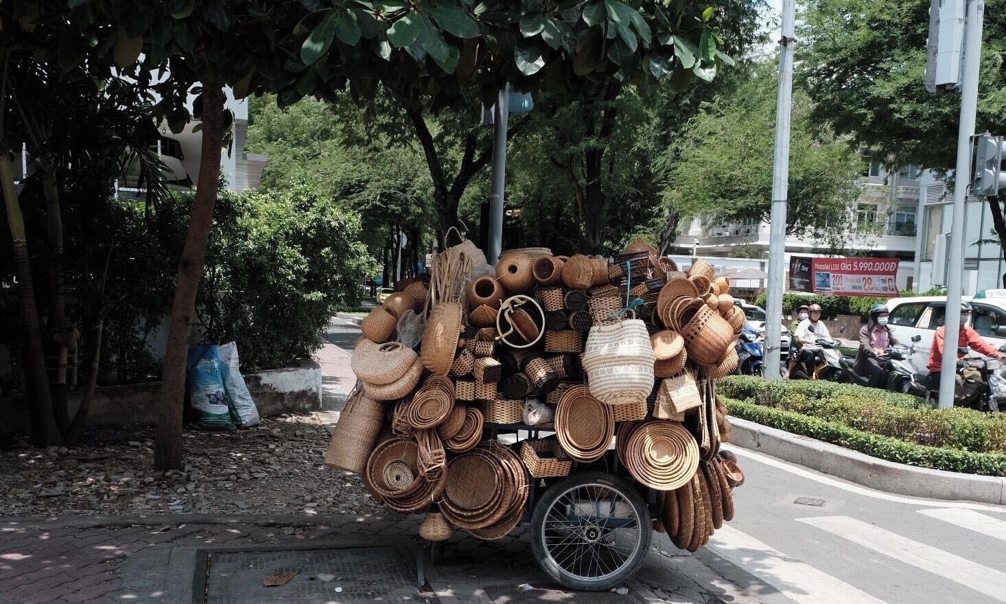 Carrinho de rua de um vendedor cheio de cestos e bolsas tecidas estacionado na calçada.
