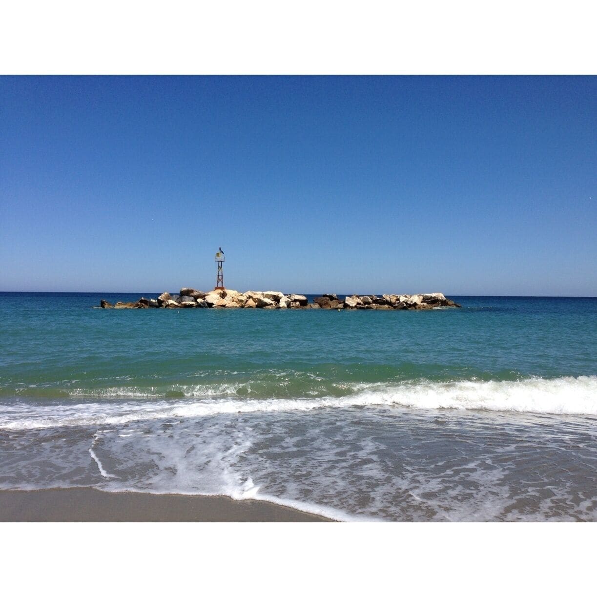 Um molhe rochoso com um farol ao longe.