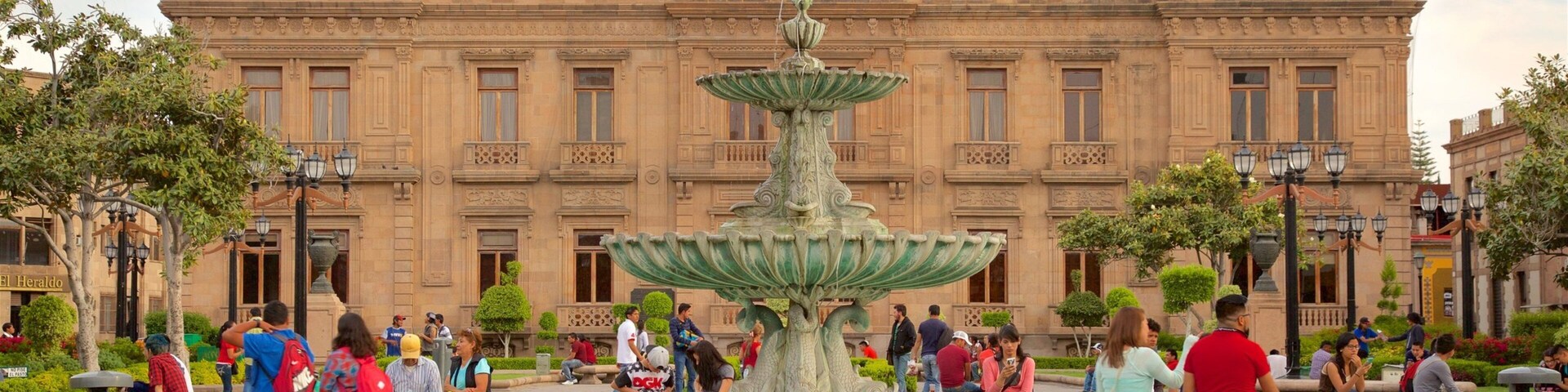 Um edifício histórico com arquitetura ornamentada e uma fonte central.