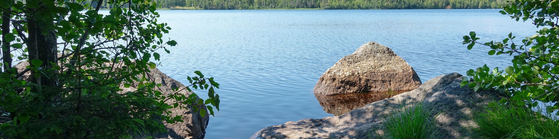 Um lago tranquilo rodeado por pedras e árvores.
