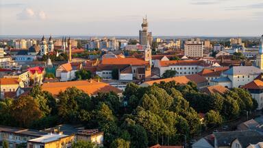 Paisagem urbana com edifícios históricos, uma torre de igreja imponente e uma mistura de arquitetura moderna e tradicional.