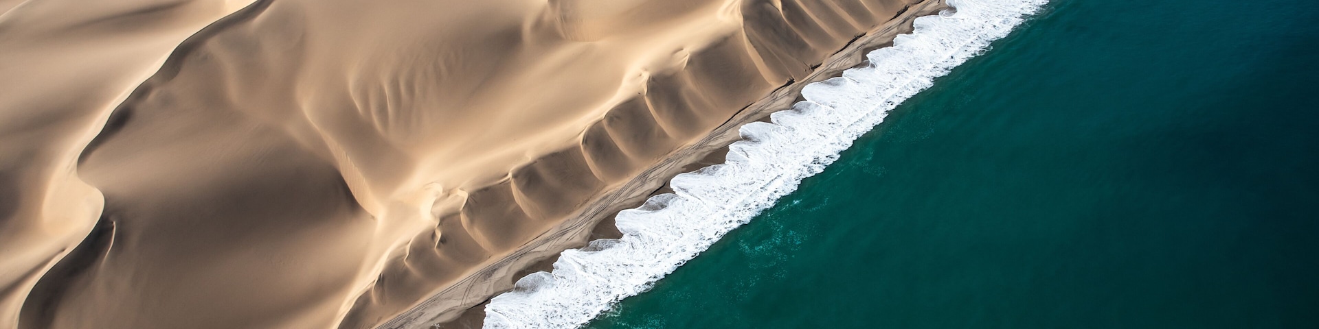 Paisagem costeira com dunas de areia e oceano azul cristalino.