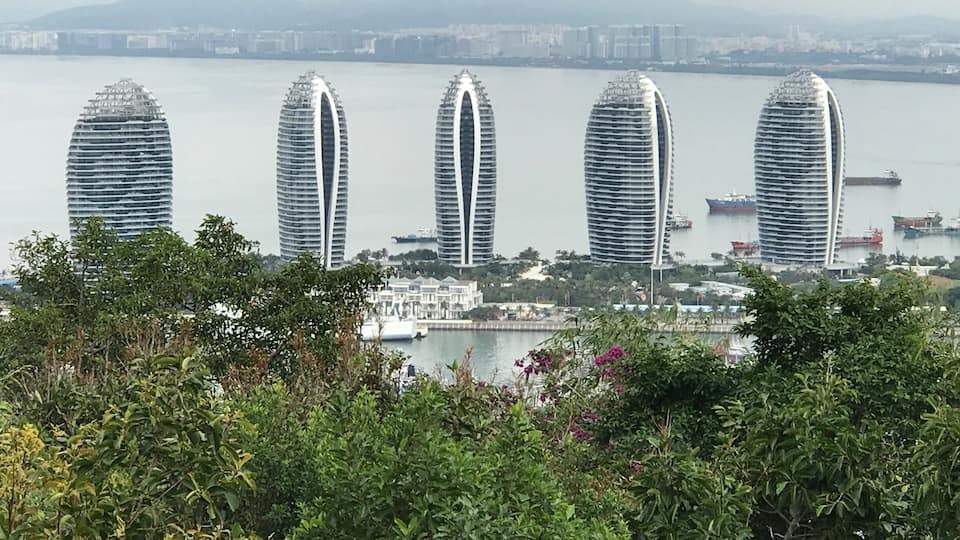 Paisagem urbana costeira com cinco arranha-céus modernos e distintos.