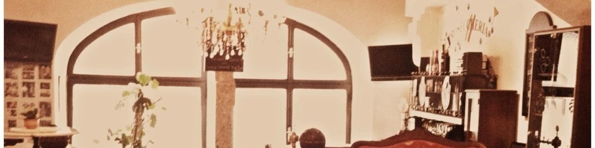 Um interior antigo com um candelabro, janelas em arco e mobiliário clássico.
