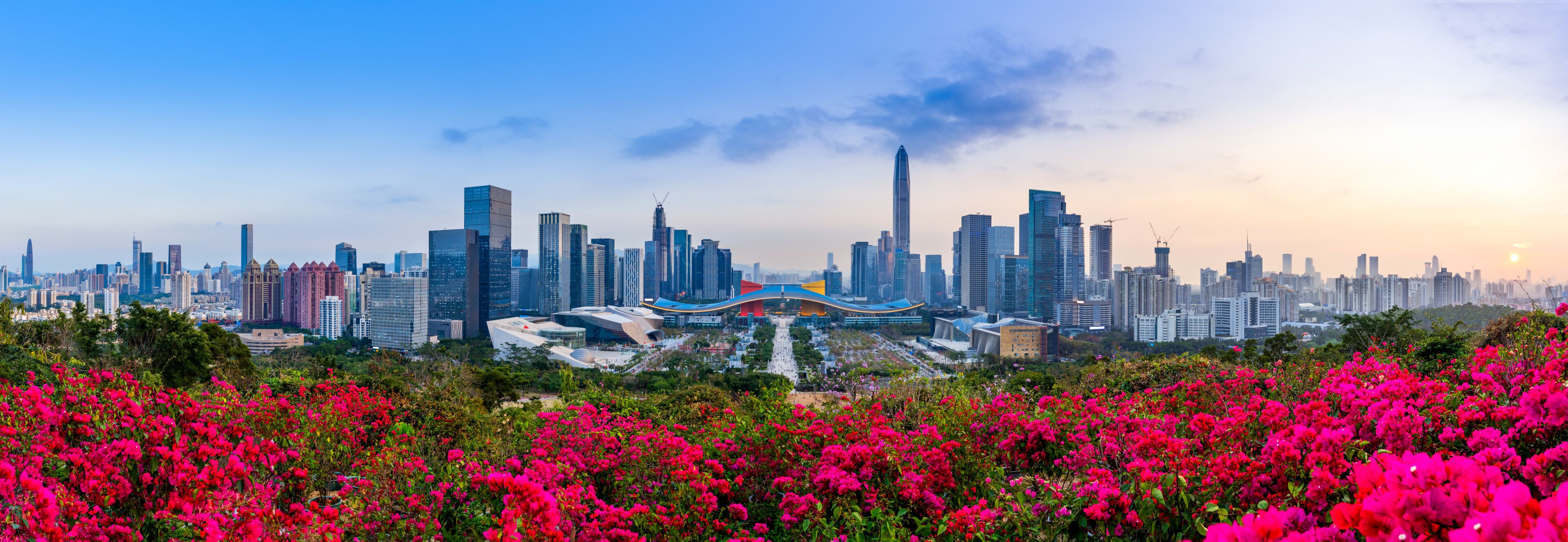 Paisagem urbana com arranha-céus modernos e um edifício curvo imponente em primeiro plano.