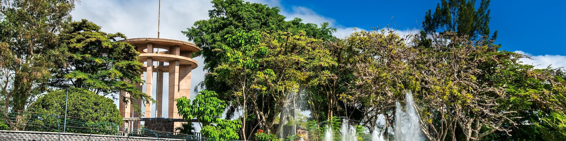 Uma fonte, um mastro de bandeira e um edifício com cúpula.