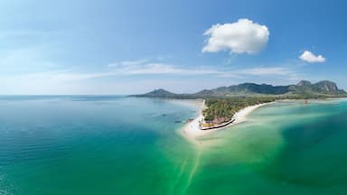 Uma ilha tropical com águas turquesa cristalinas, uma praia arenosa e uma montanha imponente.