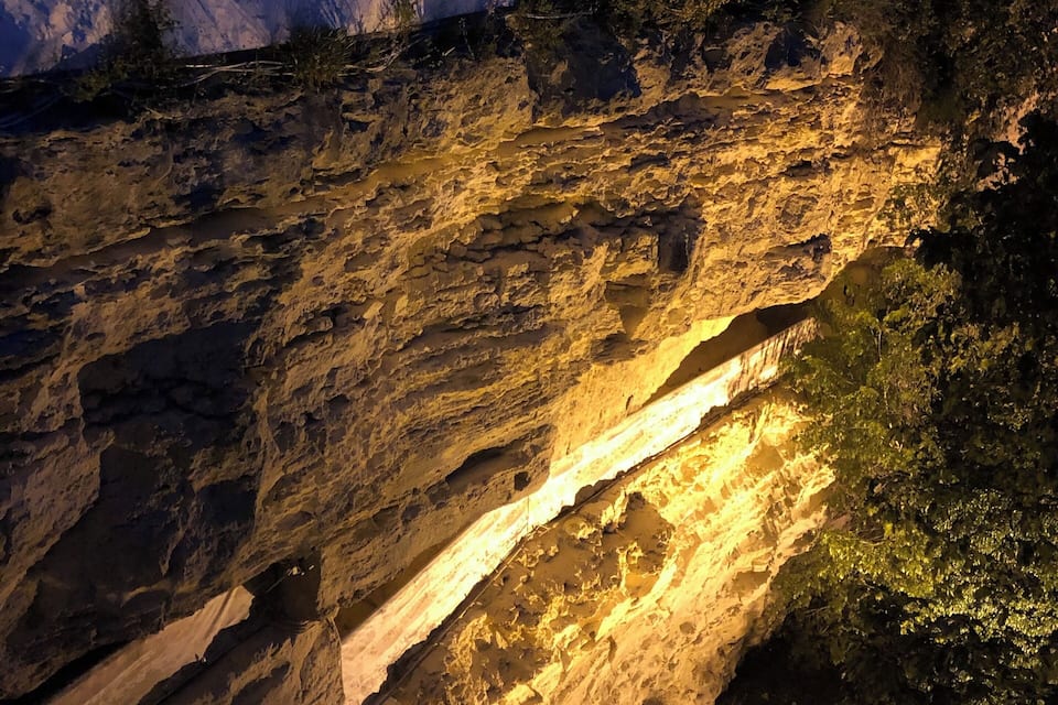 Um penhasco rochoso iluminado por luz artificial à noite.