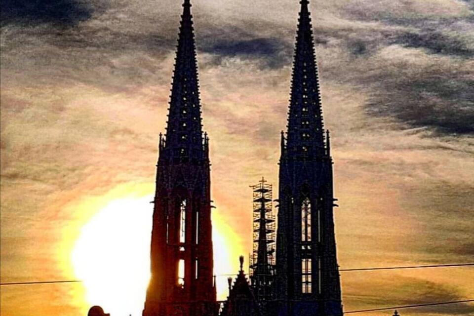 Igreja com duas torres altas recortadas contra o céu ao pôr do sol.