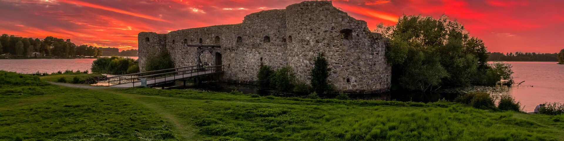 Edifício de pedra histórica à beira de um lago ao pôr do sol.