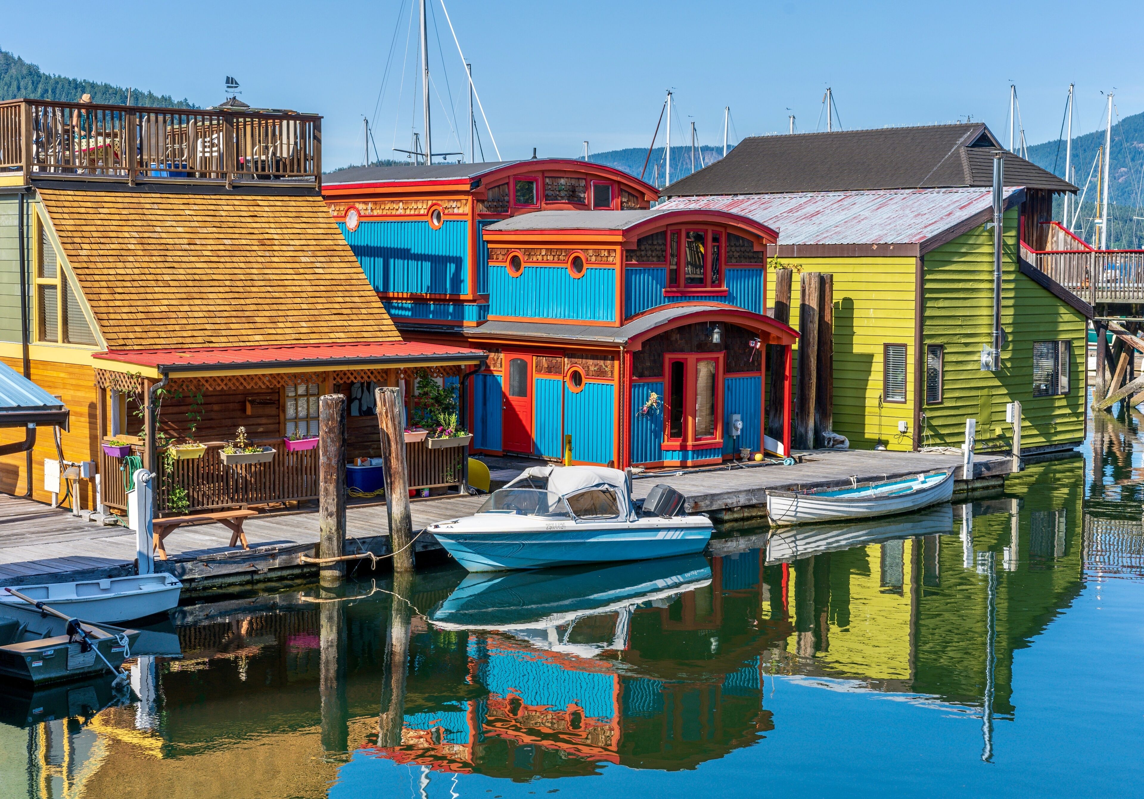 Casas de madeira coloridas à beira de um canal tranquilo com barcos atracados.