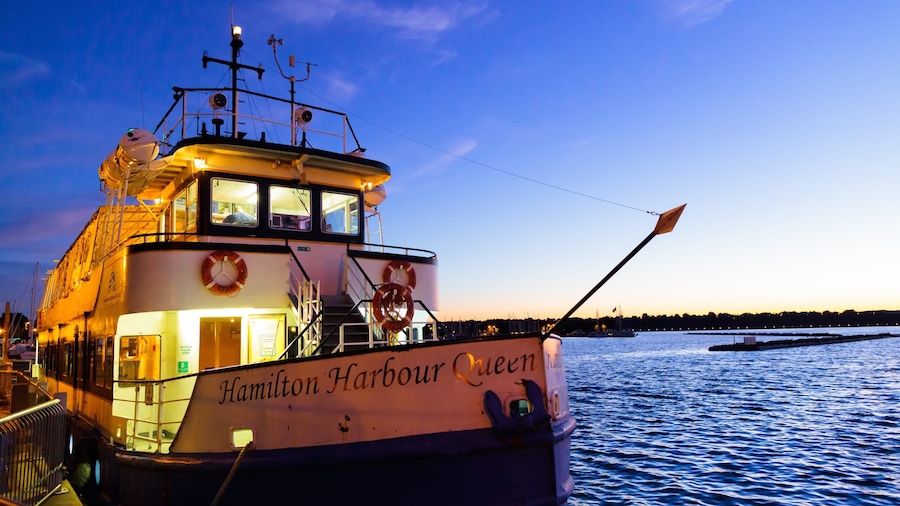 Um barco chamado 'Hamilton Harbour Queen' atracado num cais, com céu limpo e águas calmas.