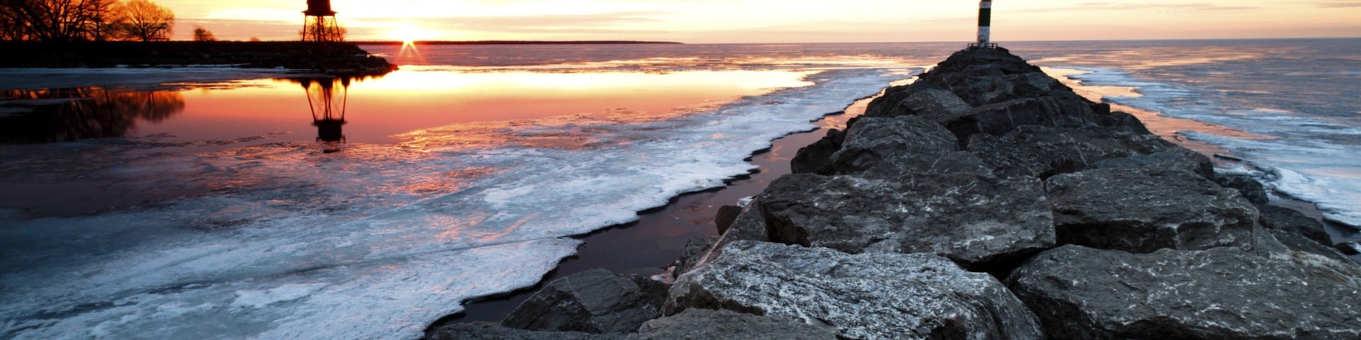 Alpena que inclui um pôr do sol, neve e um farol