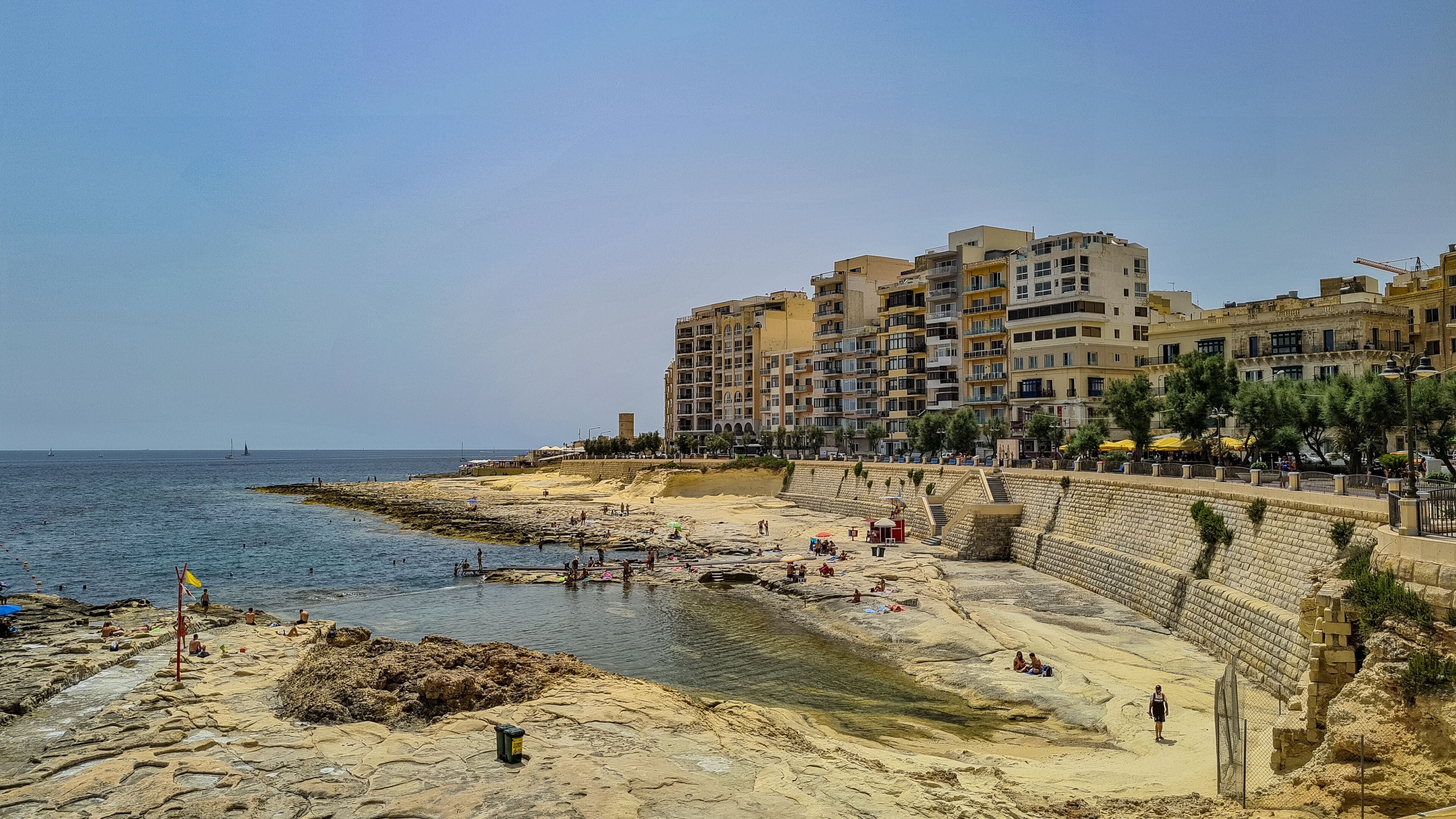 Paisagem costeira com falésias, vista para o mar e edifícios altos.